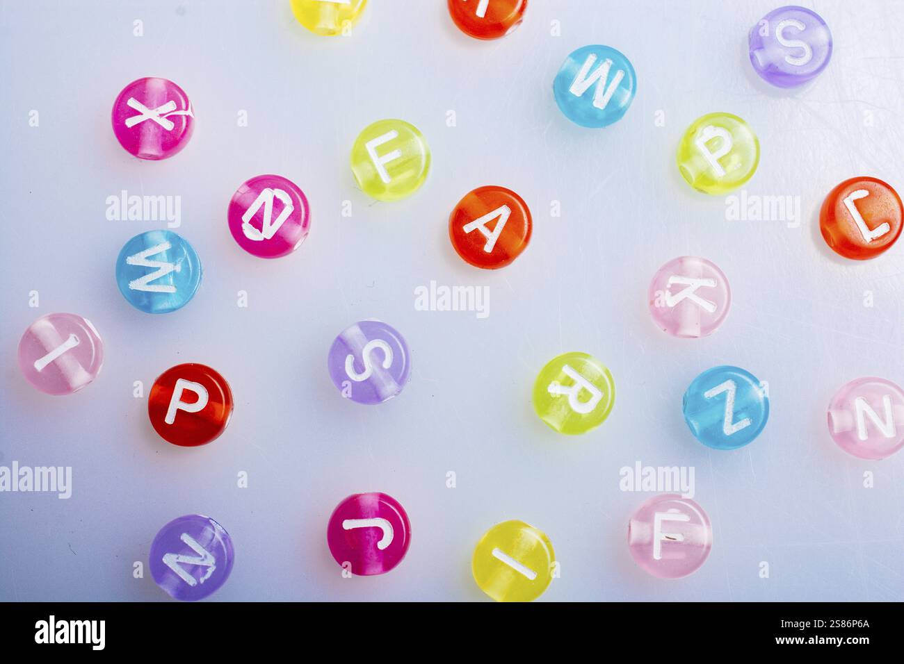 Multi color alphabet letter beads placed randomly on white background ...