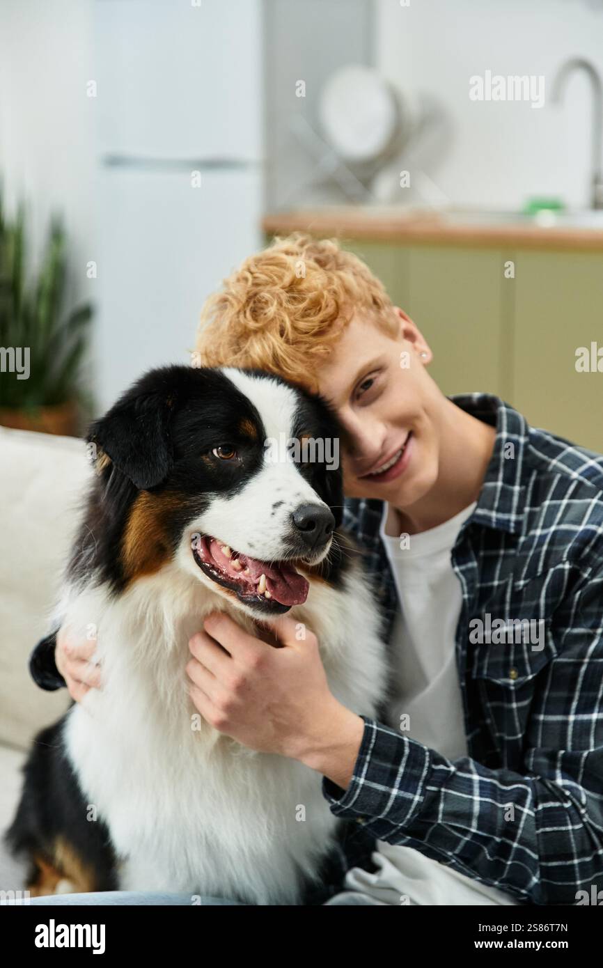 A young redhead man cuddles his adorable Australian Shepherd in a ...