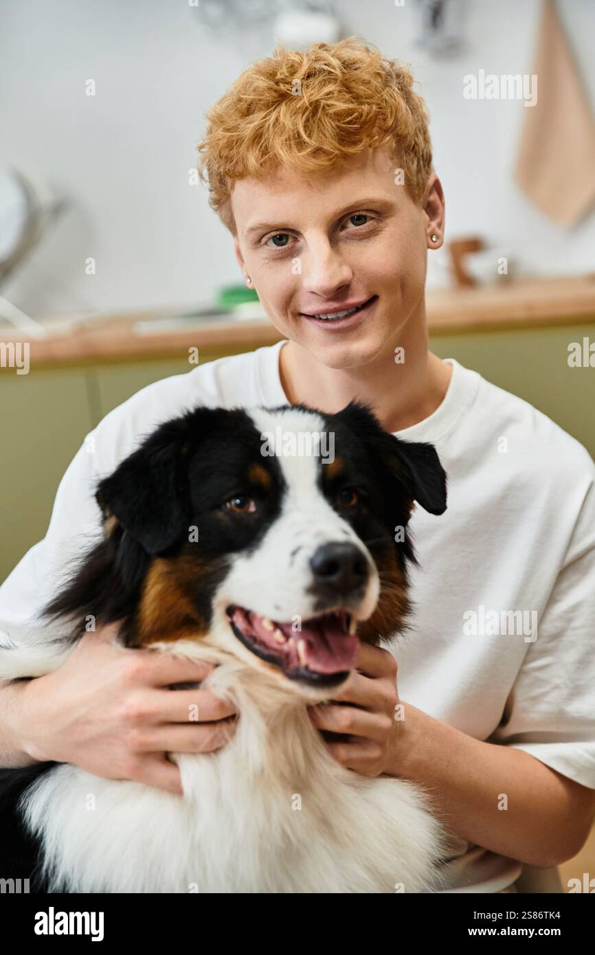 A young redhead man smiles while lovingly holding his Australian ...