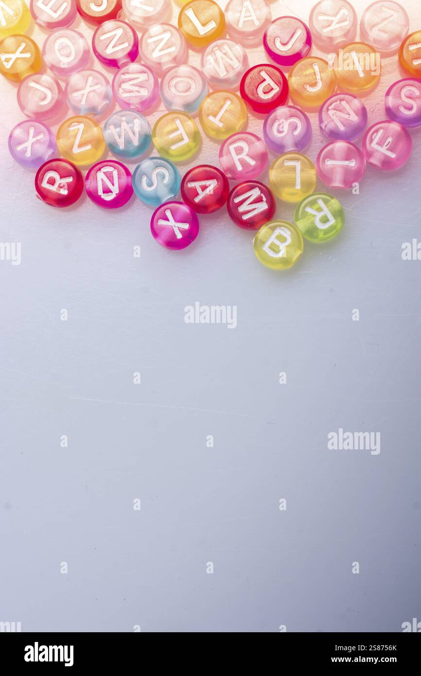 Multi color alphabet letter beads placed randomly on white background ...