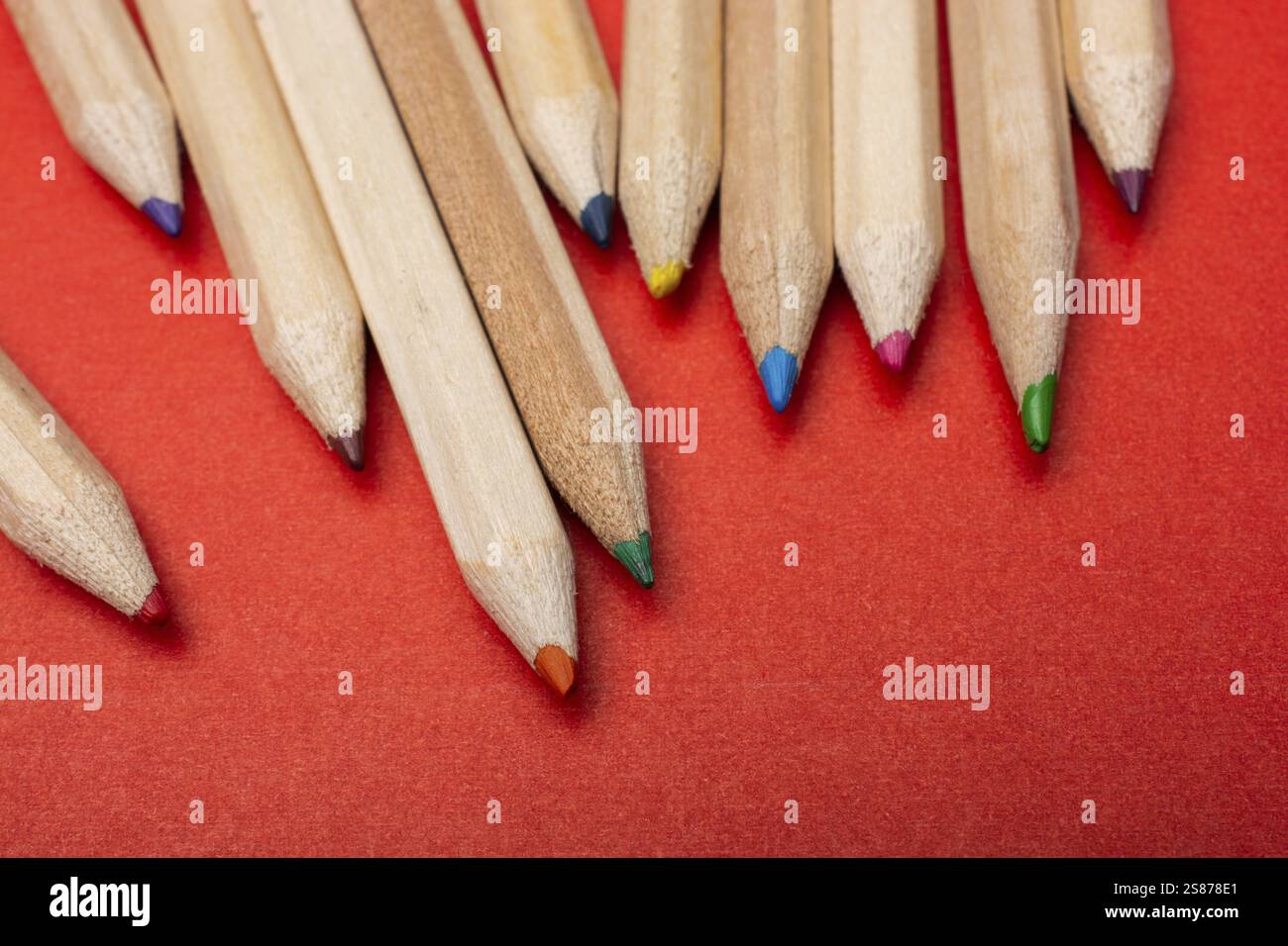 Colored pencils on red background. Many different colored pencils Stock ...