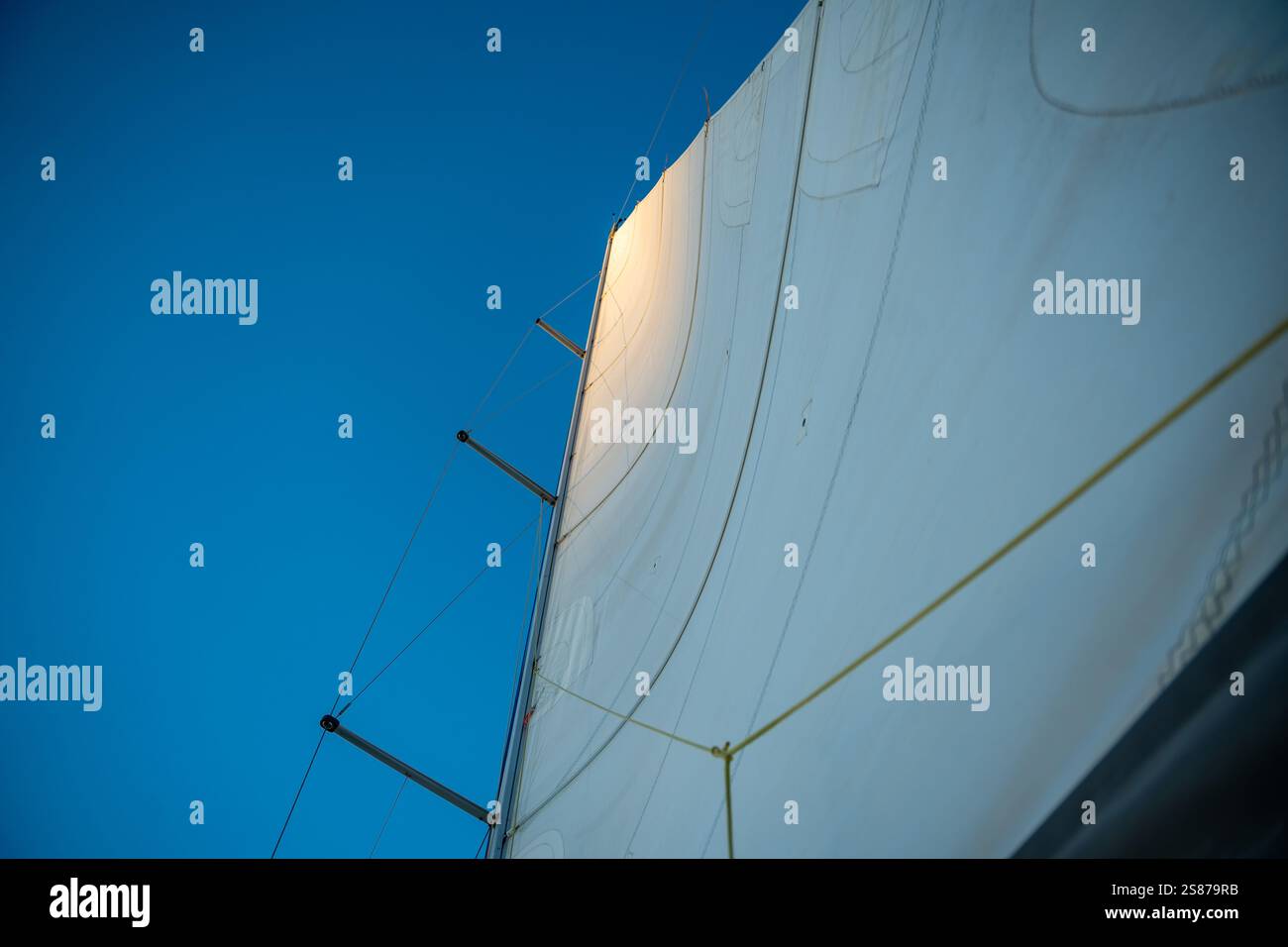 Sunlit top piece of a sail of a sailing yacht in the wind sailing on ...