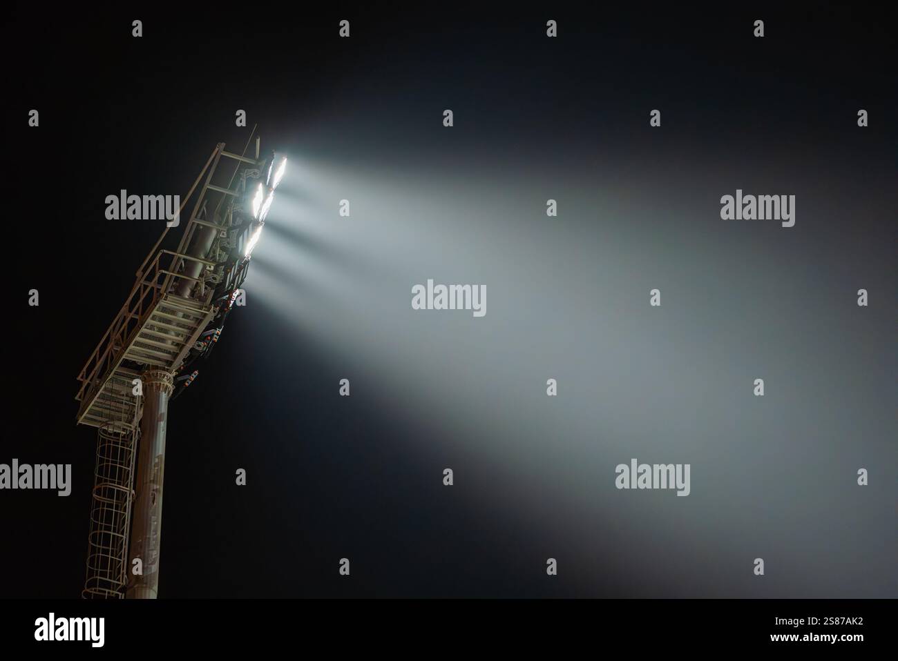 Powerful stadium lights illuminate the night sky, casting bright beams ...