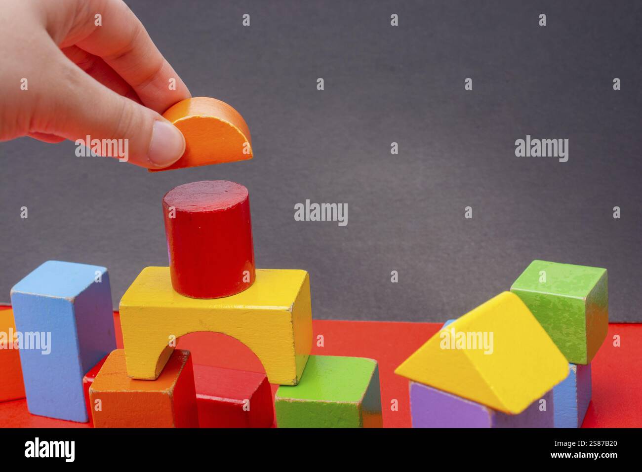 Hand building tower with colorful building blocks Stock Photo - Alamy
