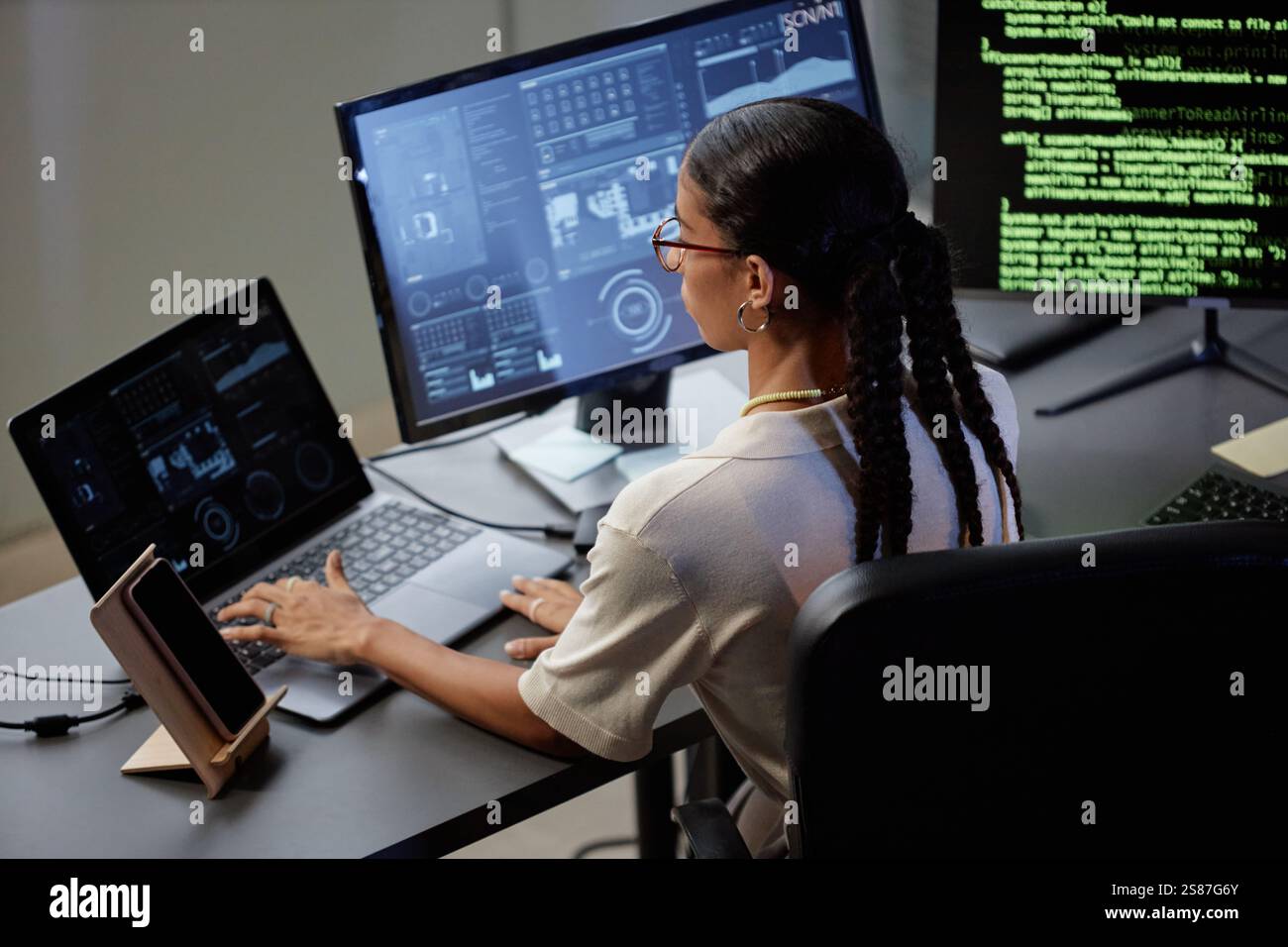 Side view of female programmer with braided hairstyle sitting at ...