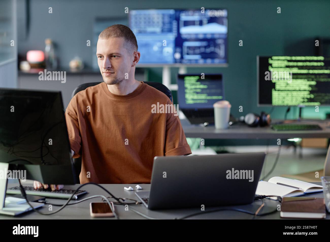 Medium shot of calm male programmer typing on computer keyboard working ...