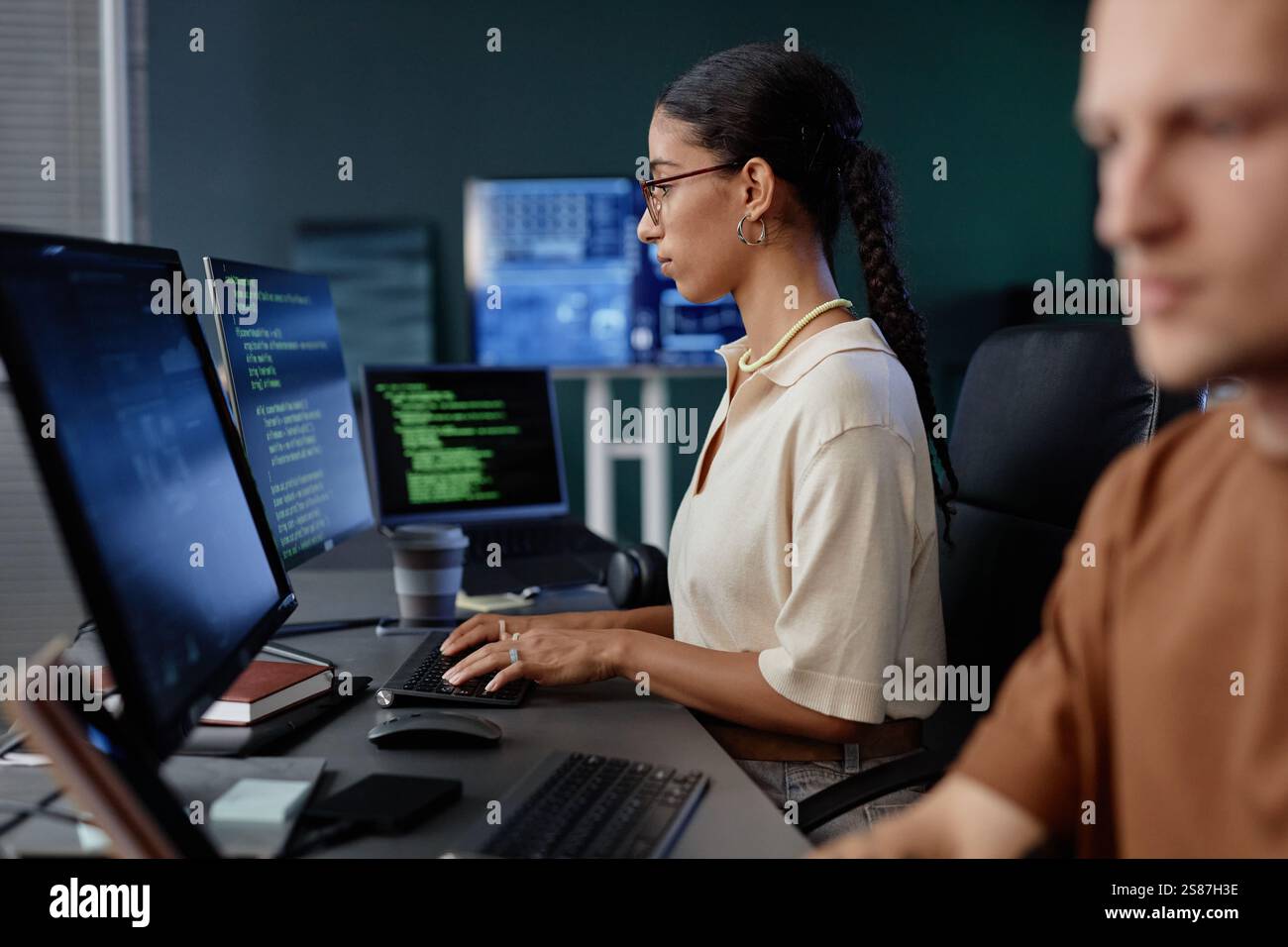 Side view of professional Middle Eastern female programmer concentrated on typing code on ...