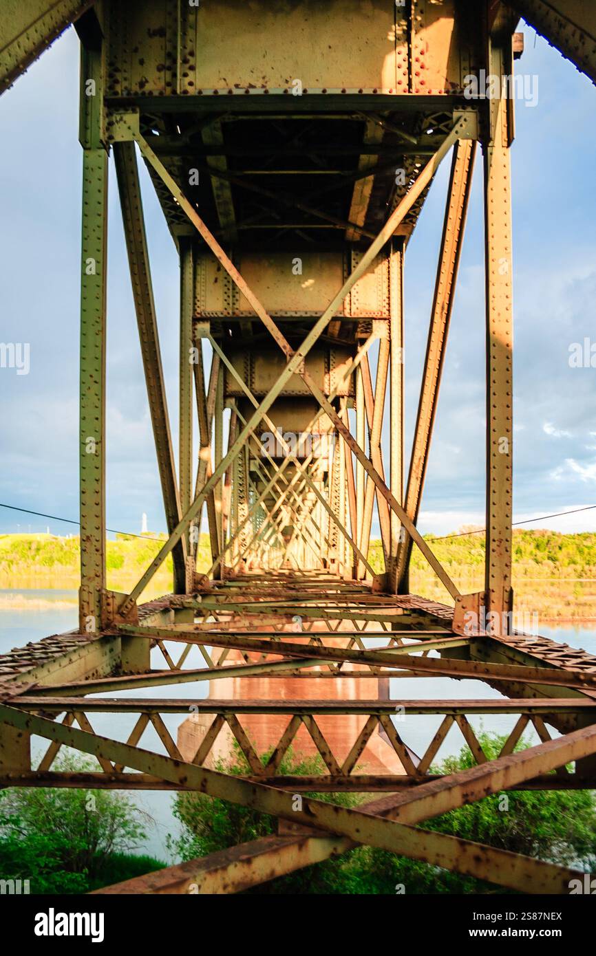 The bridge is old and rusted, with a lot of metal bars and wires. The ...