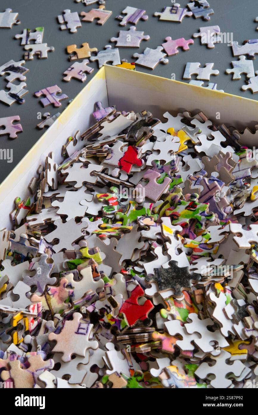 Jigsaw puzzle pieces unassembled in a box and on an assembly board, USA ...