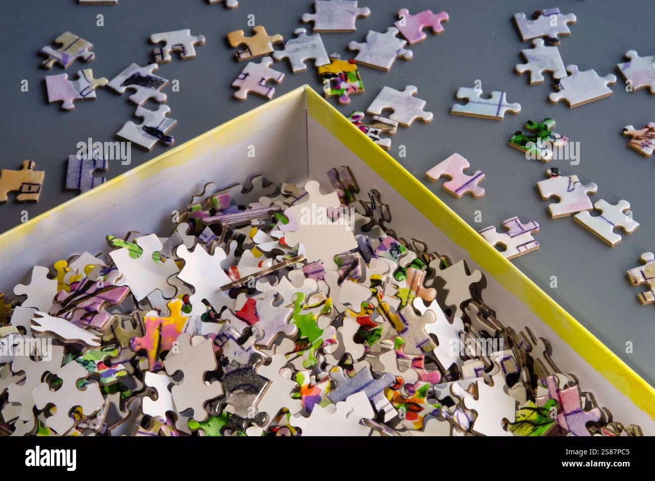 Jigsaw puzzle pieces unassembled in a box and on an assembly board, USA ...
