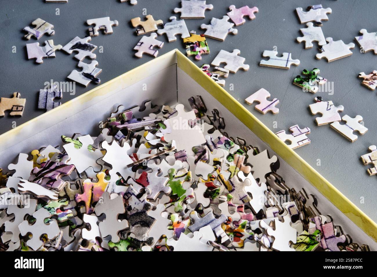 Jigsaw puzzle pieces unassembled in a box and on an assembly board, USA ...