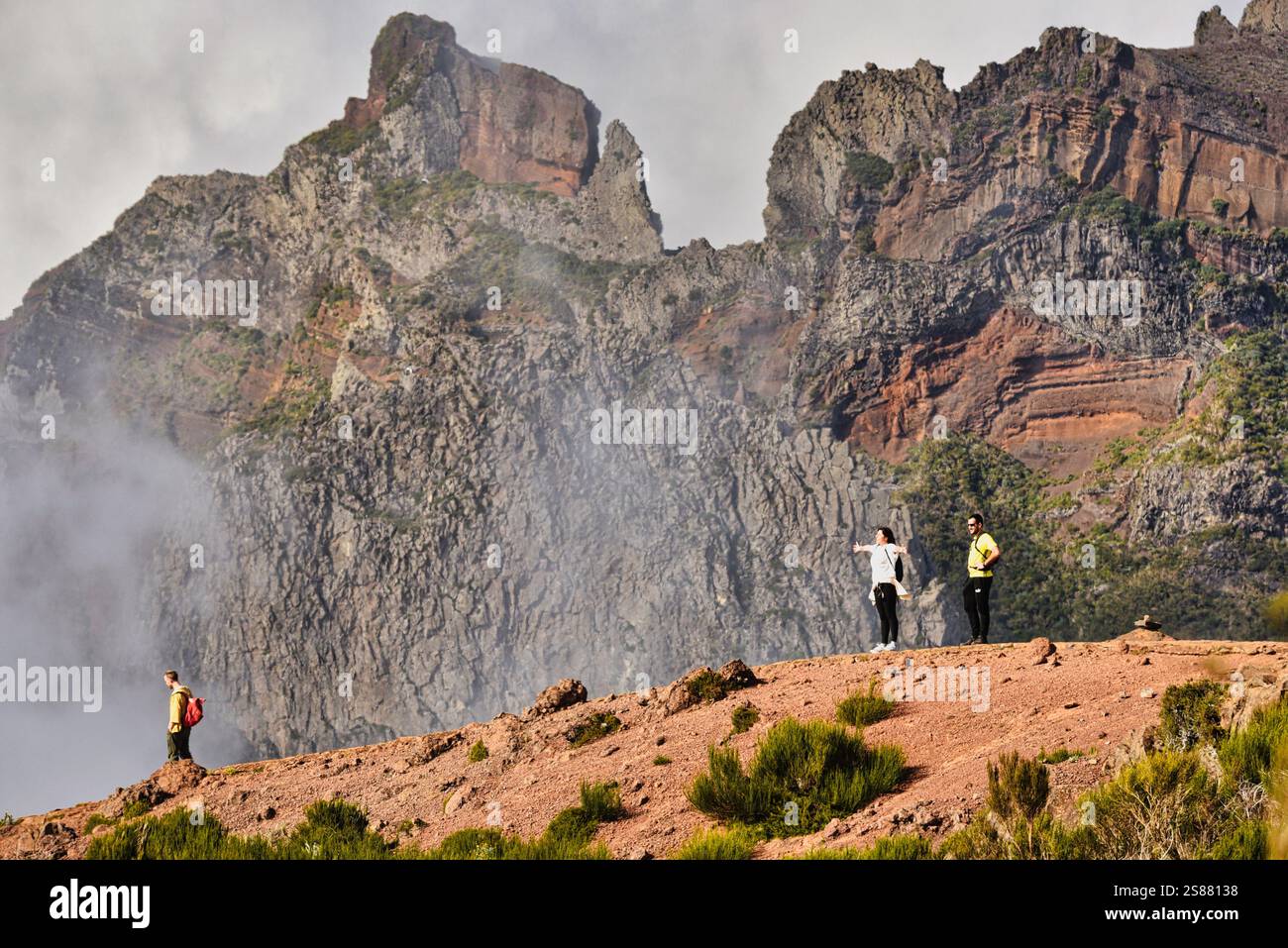 Hikers on trail pathway along jagged volcanic cliffs on Pico Areeiro ...