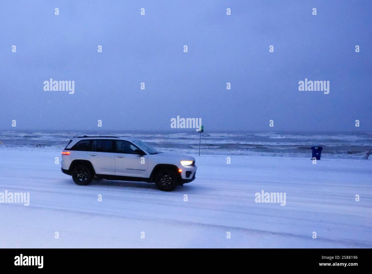 An SUV drives along snow-covered Seawall Blvd. during an icy winter ...