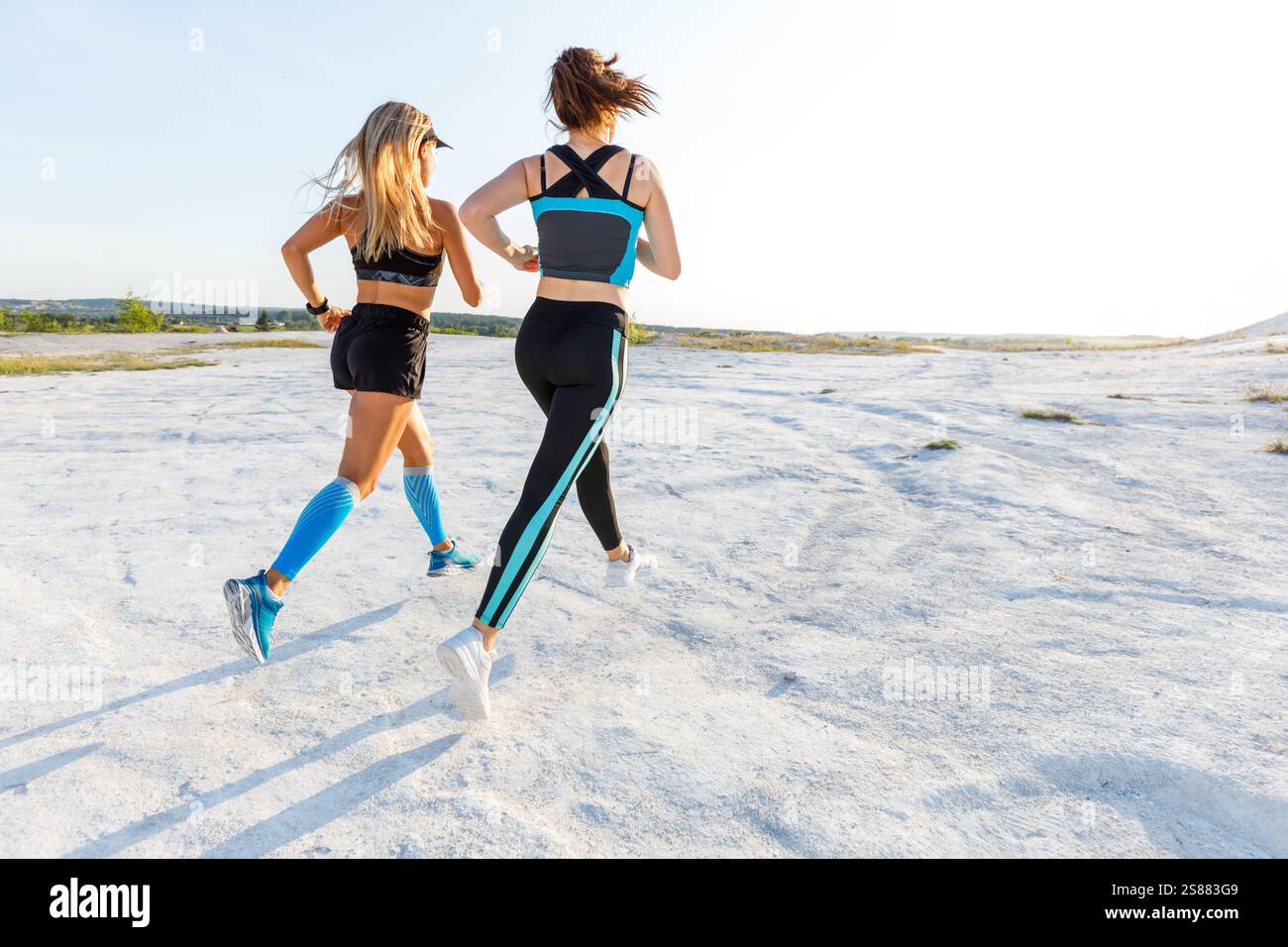 Two young women jogging together in a vast white landscape under a ...