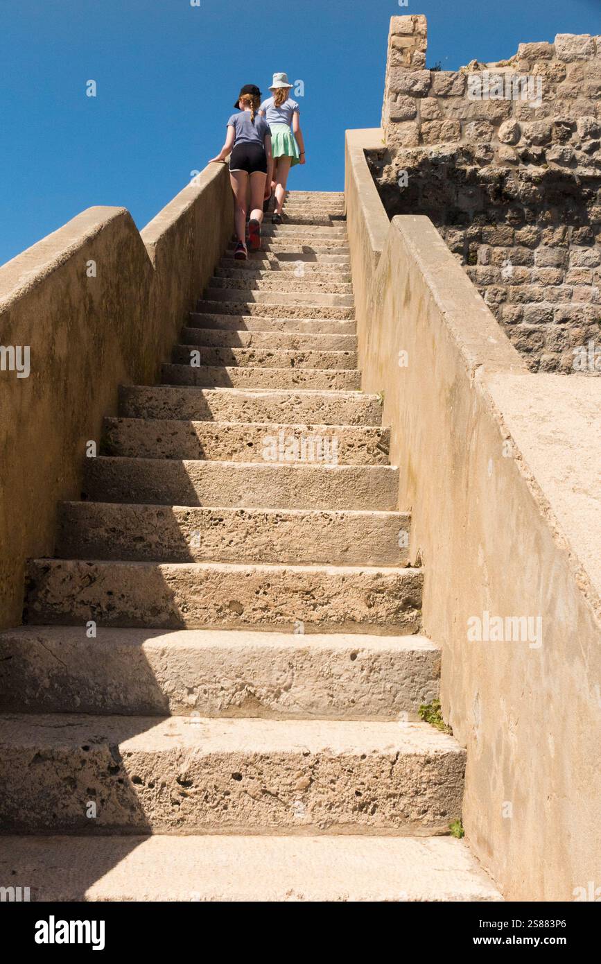 Children / kids climb stone steps / stairs on historic city wall ...