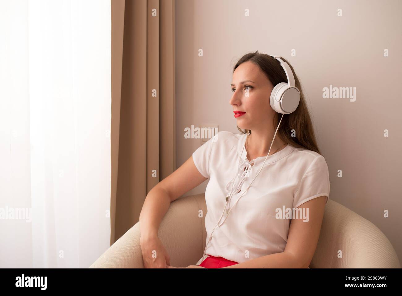 Woman enjoying music while sitting in a cozy chair by the window Stock ...