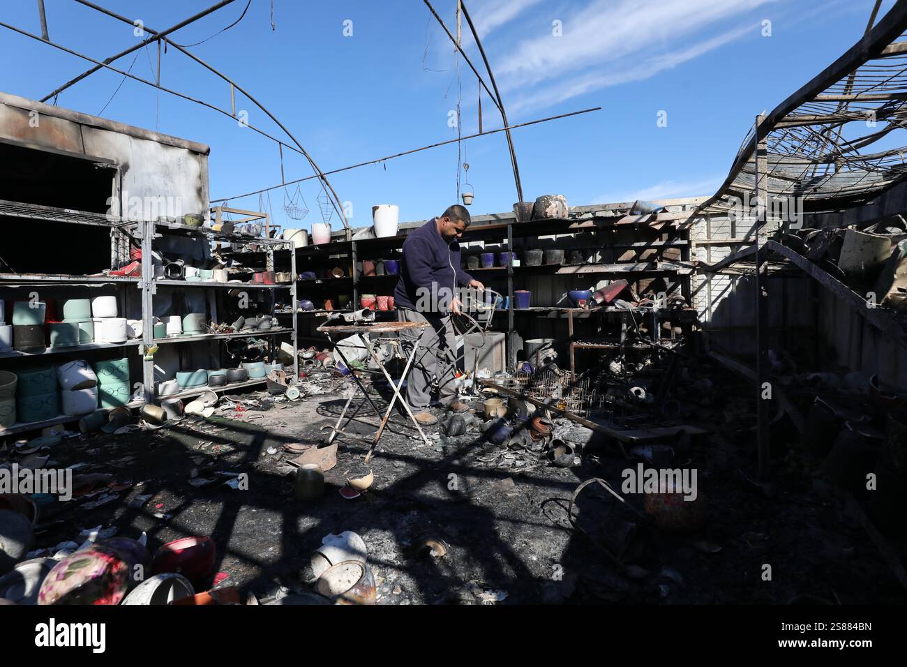 Qalqilya. 21st Jan, 2025. A man checks a burned place after a raid by ...