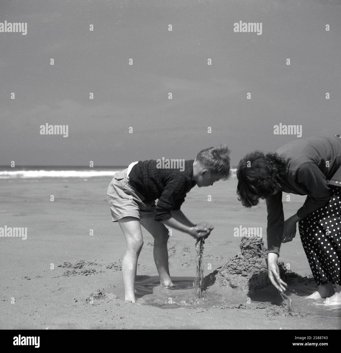 1960s, historical, at the coast, a boy with his mother on a large flat ...