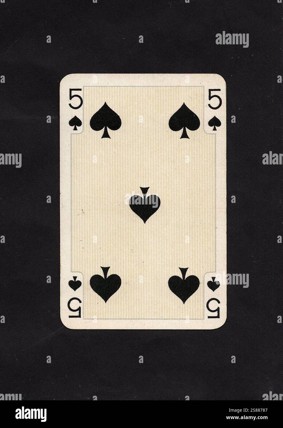 An antique five of spades playing card isolated on a black background ...