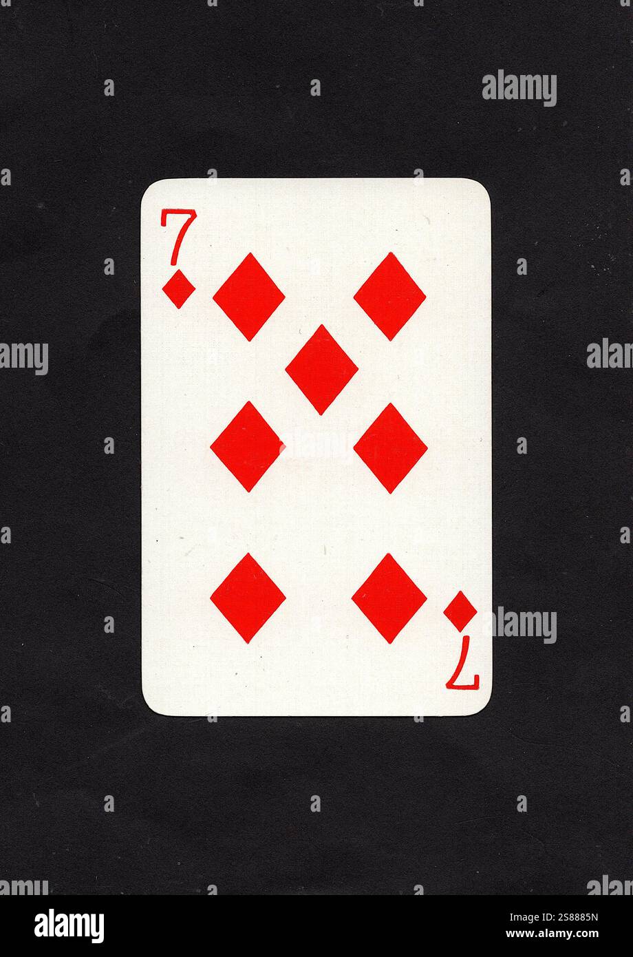 A vintage seven of diamonds playing card isolated on a black background ...