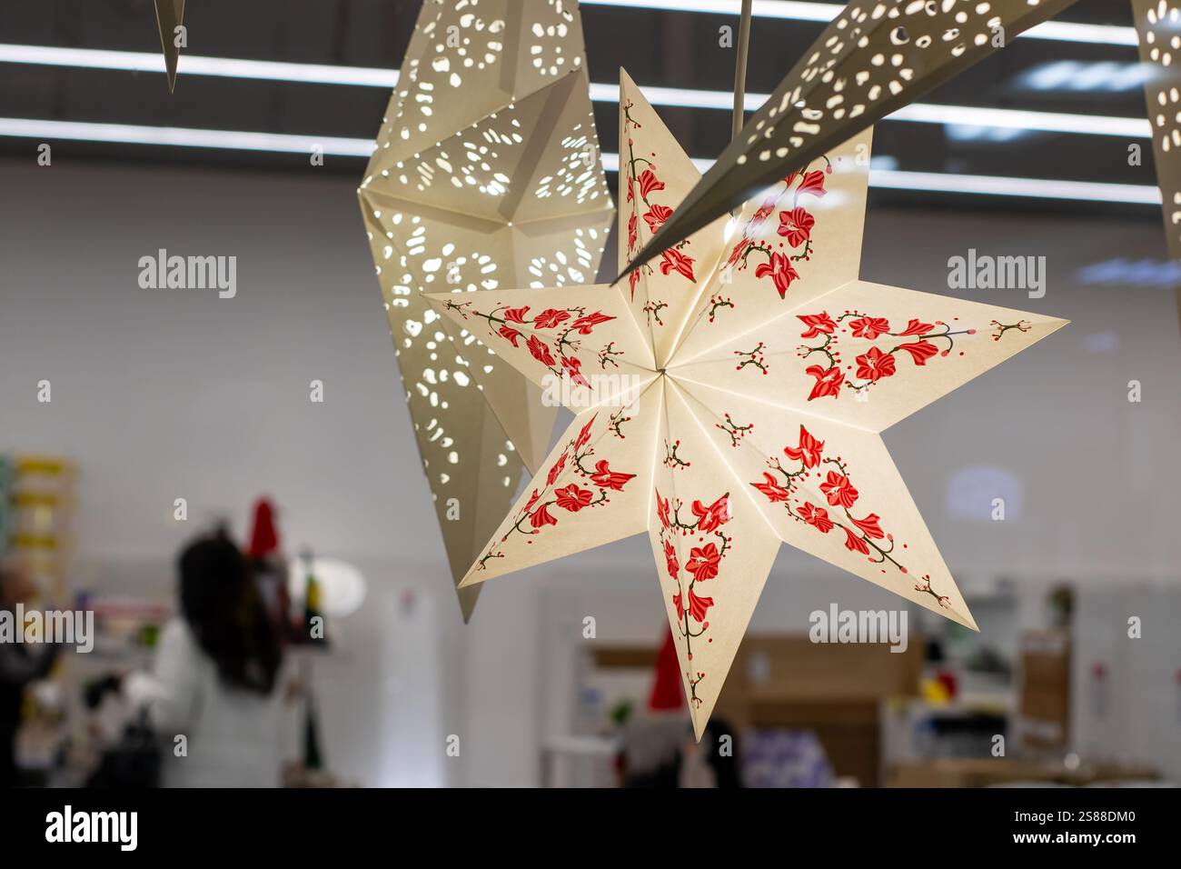 From the ceiling hangs a beautiful white star adorned with vibrant red ...