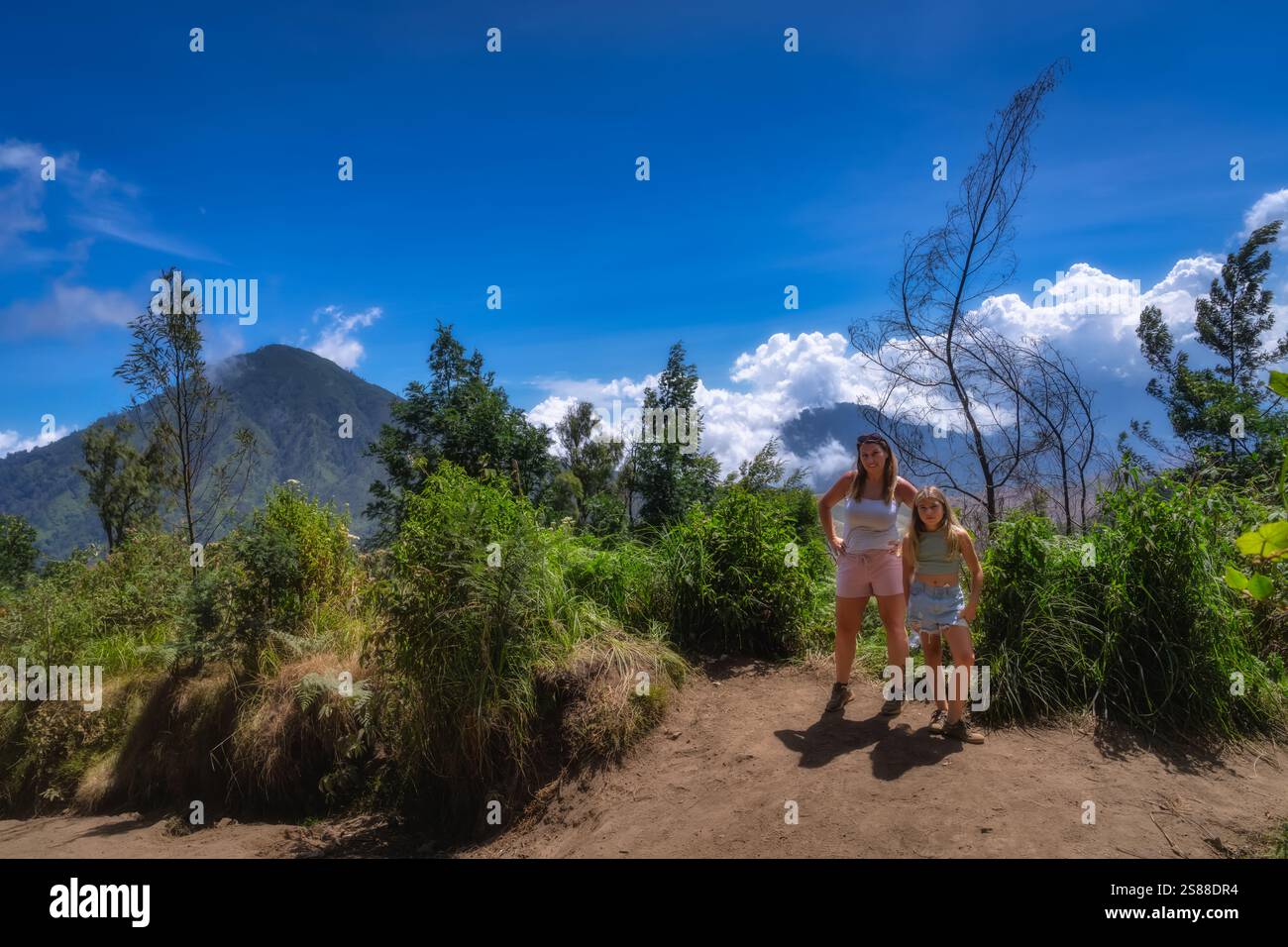 Two friends pose joyfully against a stunning mountain backdrop, with ...