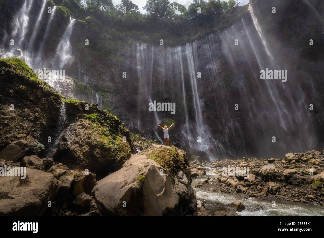 A stunning Tumpak Sewu waterfall cascades down majestic cliffs ...