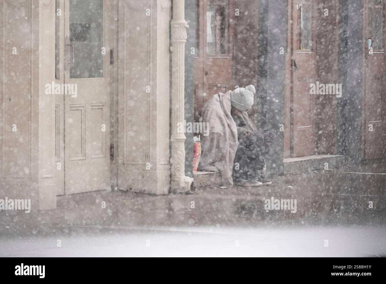 A homeless man sits in a doorway as snow falls in the French Quarter in ...