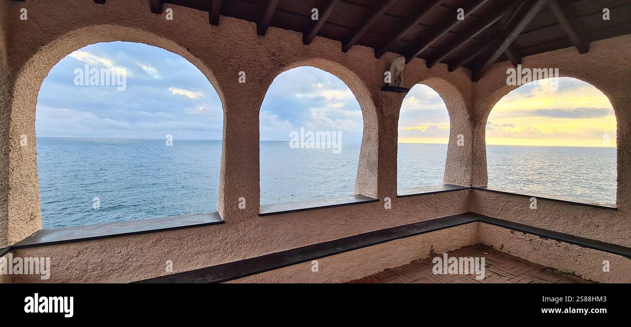 Beautiful coastal view through arched windows with sun setting over the ...