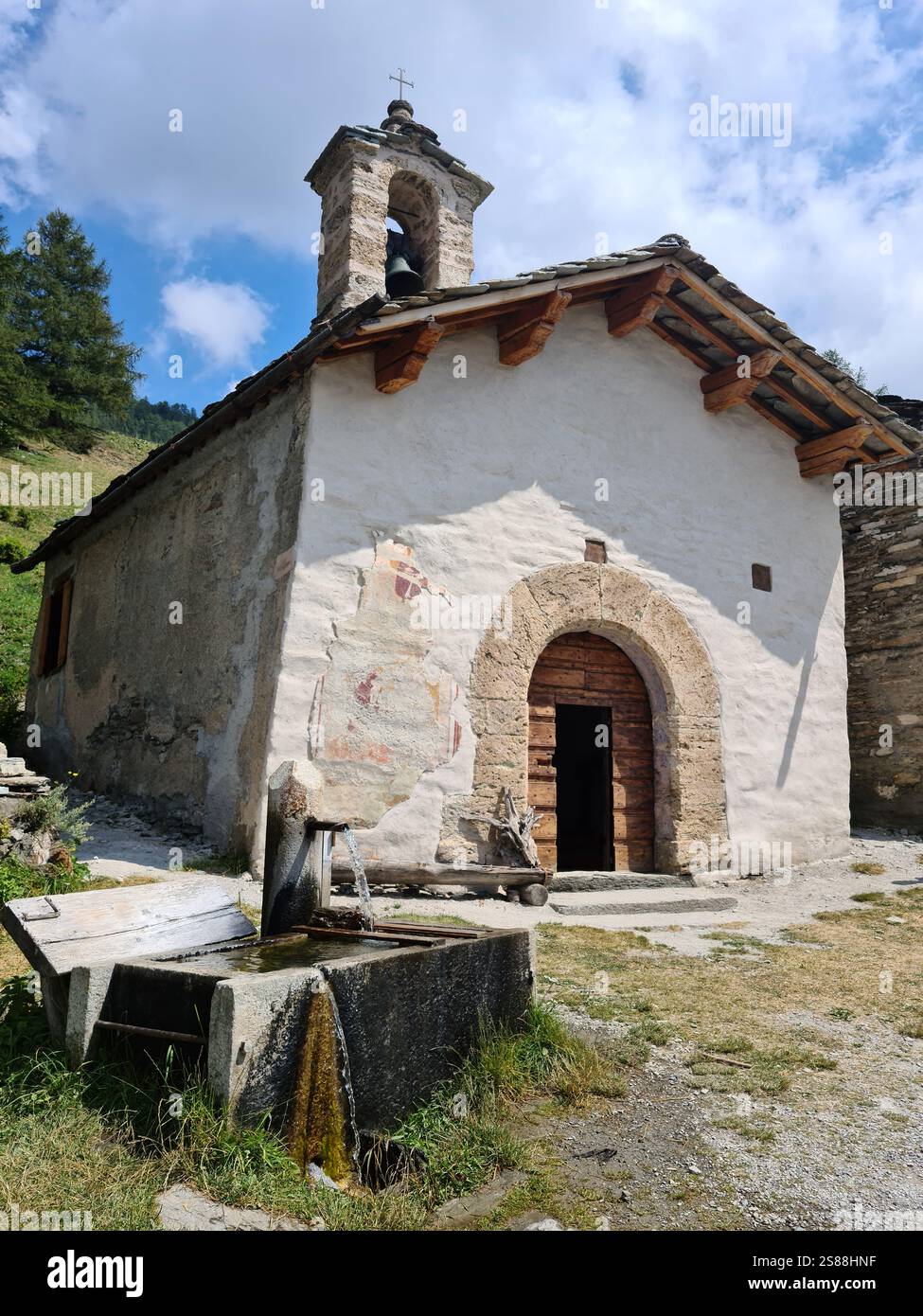 A picturesque, very simple mountain church with a fountain whose water ...