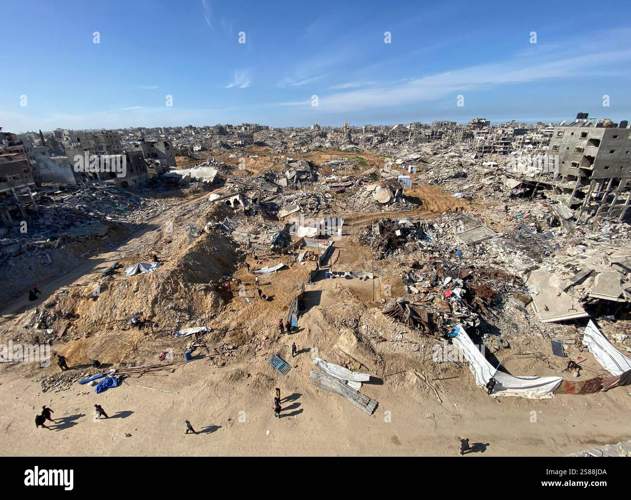People walk past the rubble of collapsed buildings at the Jabalia camp ...