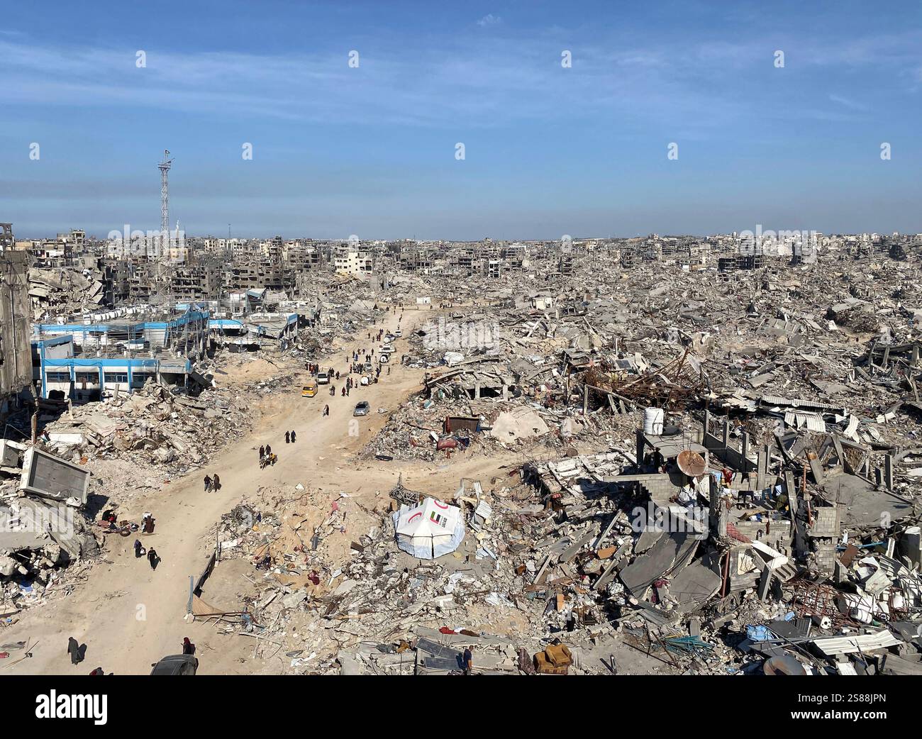 People walk past the rubble of collapsed buildings at the Jabalia camp ...