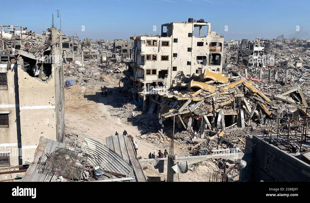 People walk past the rubble of collapsed buildings at the Jabalia camp ...