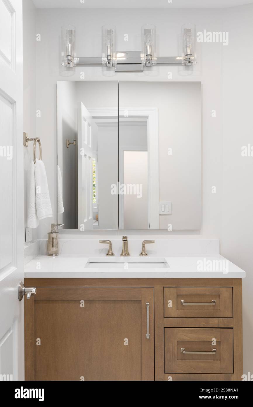A bathroom detail with an oak cabinet, bronze faucet on a white marble ...
