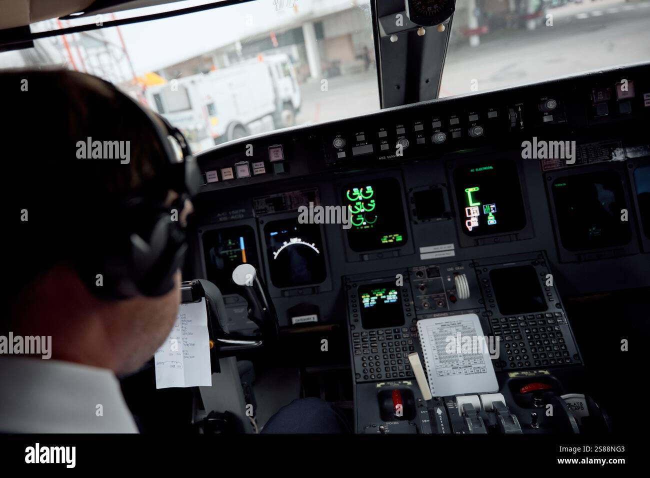 A pilot inside the cockpit of a commercial aircraft prepares for flight ...