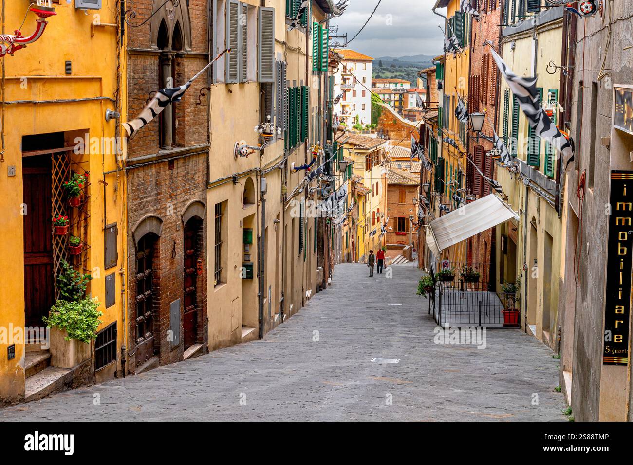 People walking up Via di Vallerozzi , a steep street in Siena, which is ...