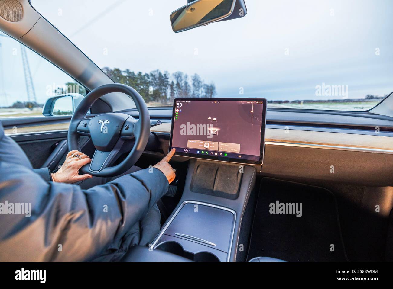 Tesla Model Y driver interacting with touchscreen display, showcasing ...