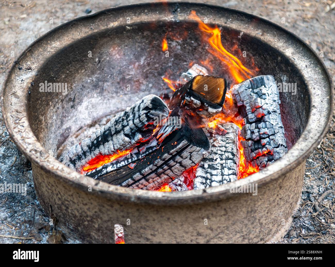 roasting hot dogs over campfire pit and grill, smoke bbq and pile of ...