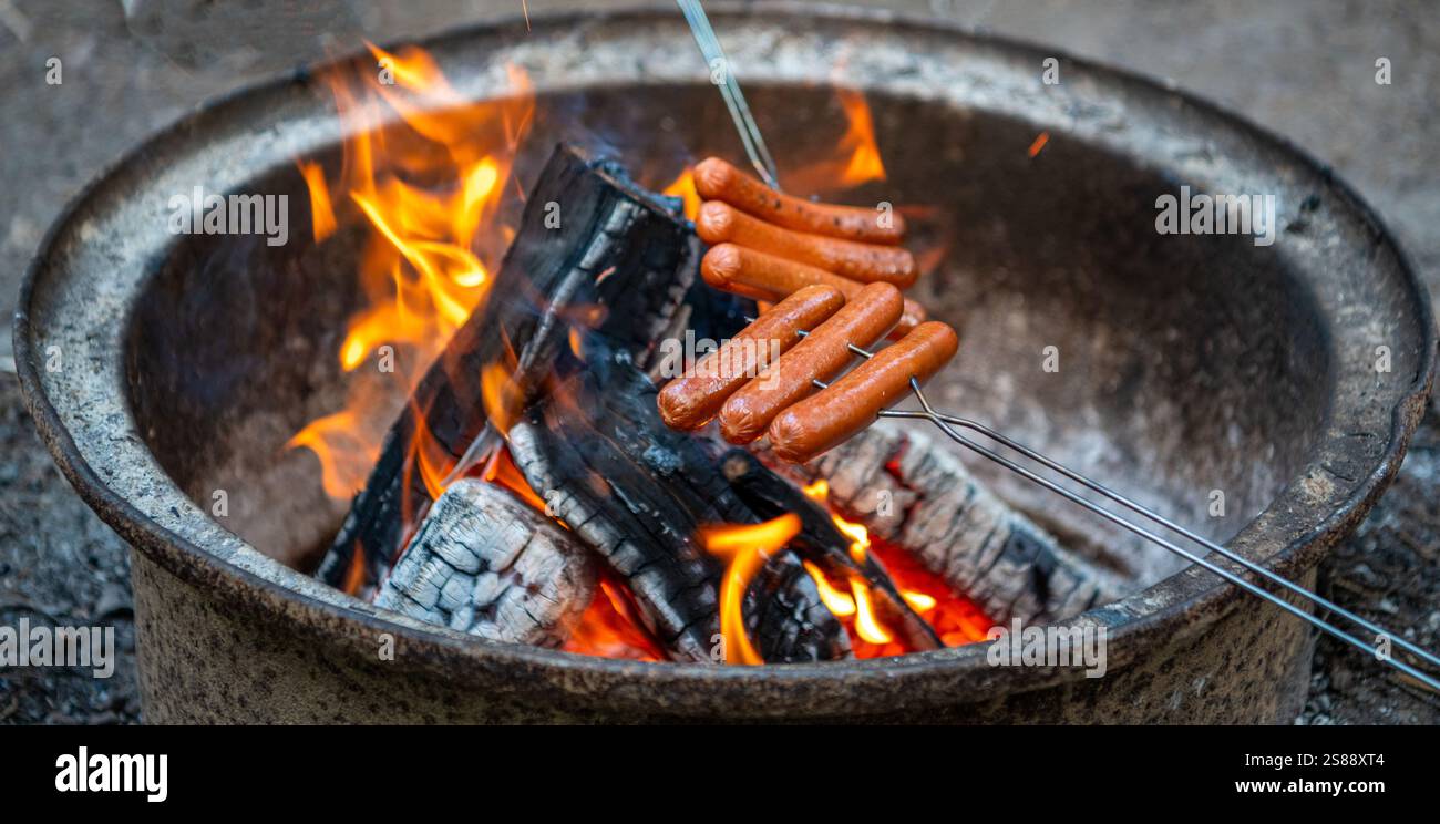 roasting hot dogs over campfire pit and grill, smoke bbq and pile of ...