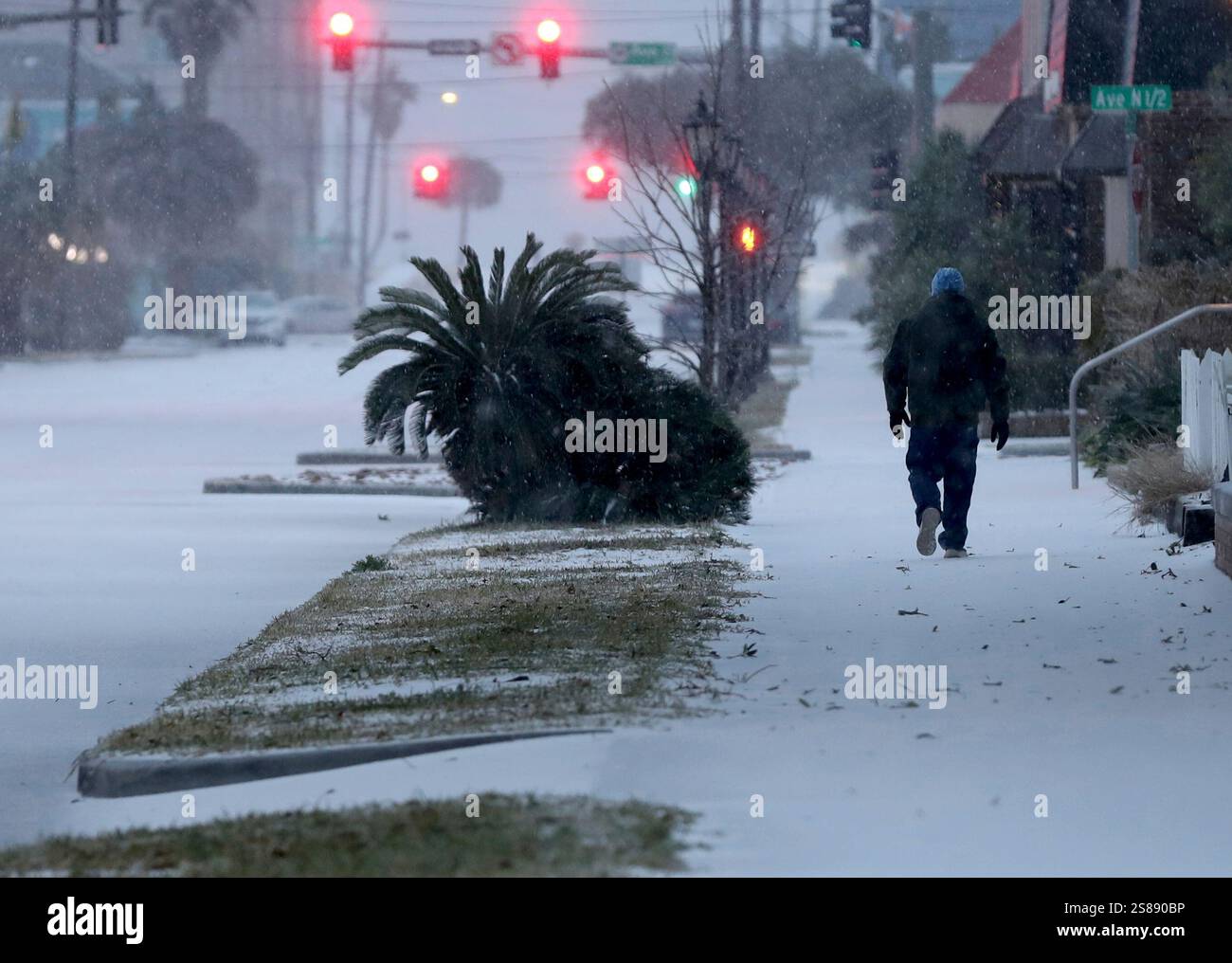 A man walks along a snow and sleet covered sidewalk in Galveston, Texas ...
