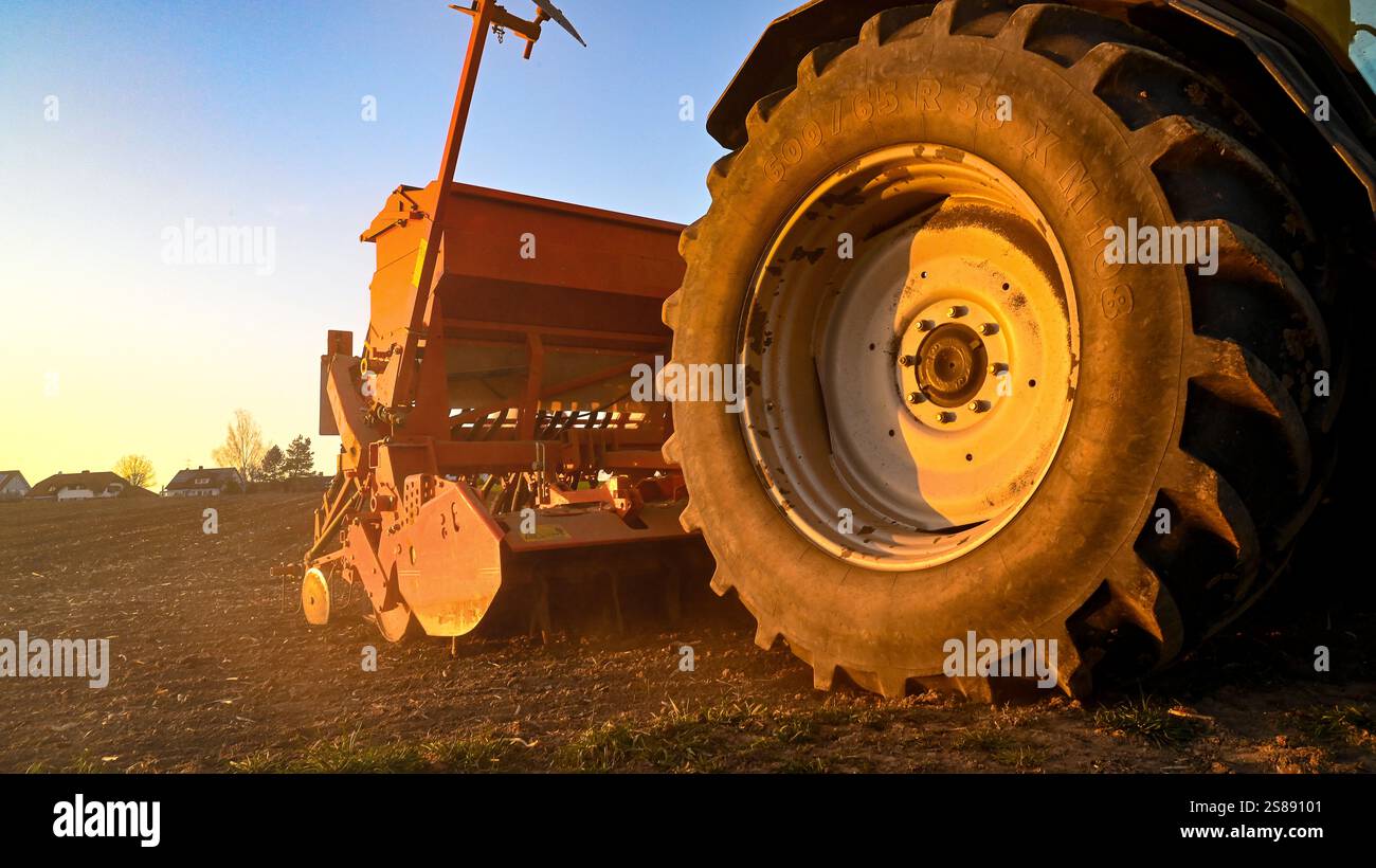 Farmer with tractor driving through a puddle in the meadow while mowing ...