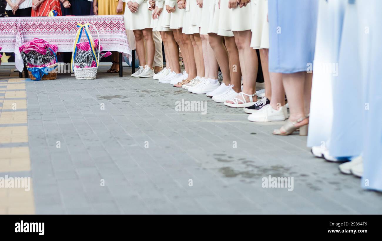 A row of women, dressed in simple white dresses and white shoes, stand ...