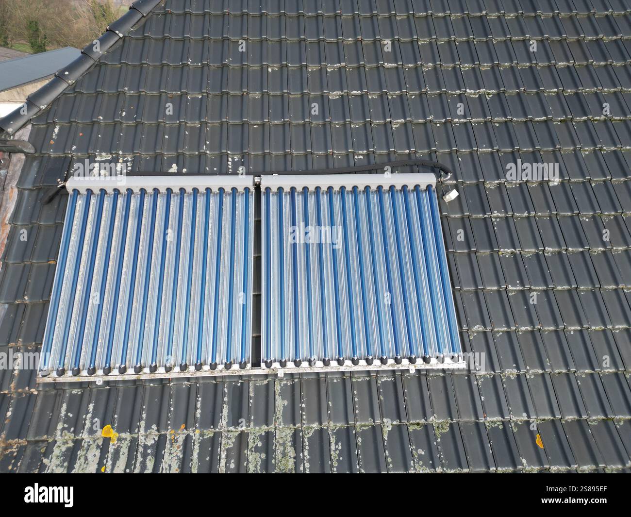 A blue solar panel is installed on the roof of a house. The panel is ...
