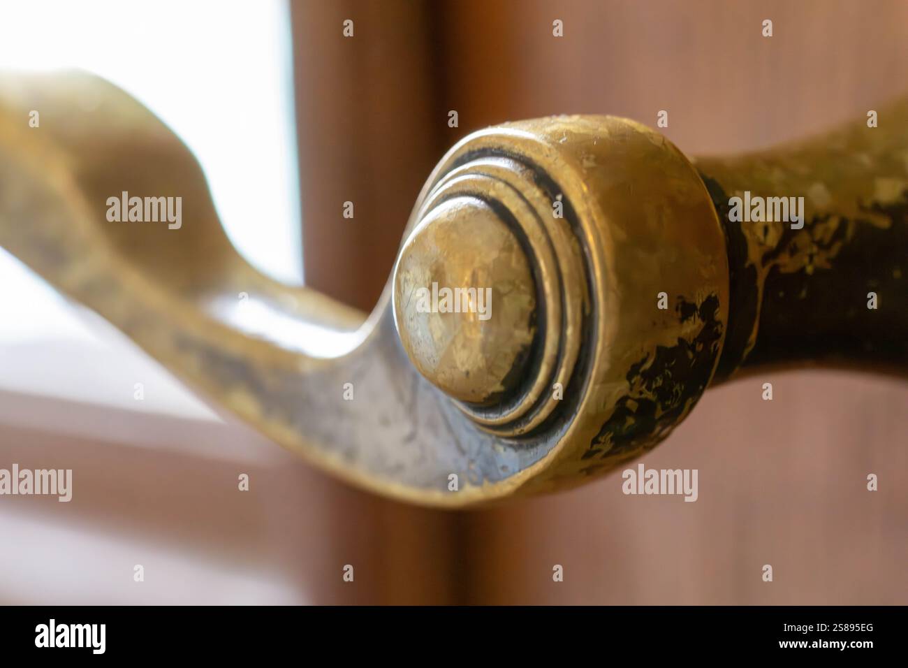 A brass handle with a silver knob. The knob is slightly worn and the ...