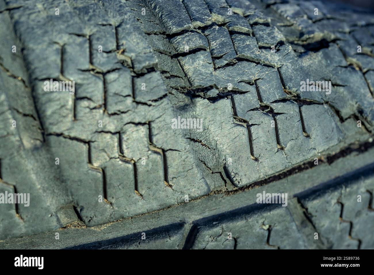 The tire has a lot of wear and tear, with many cracks and grooves. The ...