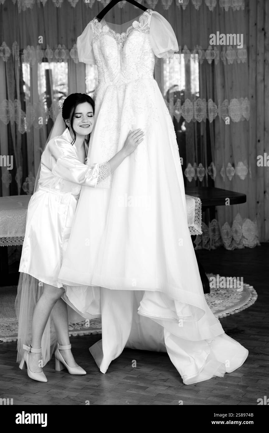 A bride-to-be in a silk robe tenderly embraces her stunning wedding ...