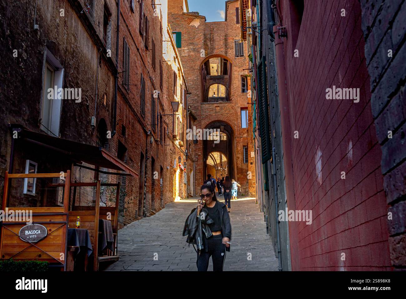 A woman walking down the steep narrow street of Via della Galluzza , a ...