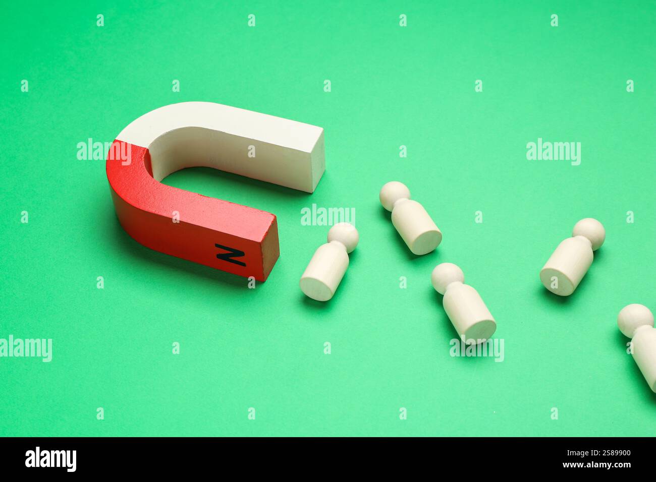 Magnet attracting human figures on green background Stock Photo - Alamy