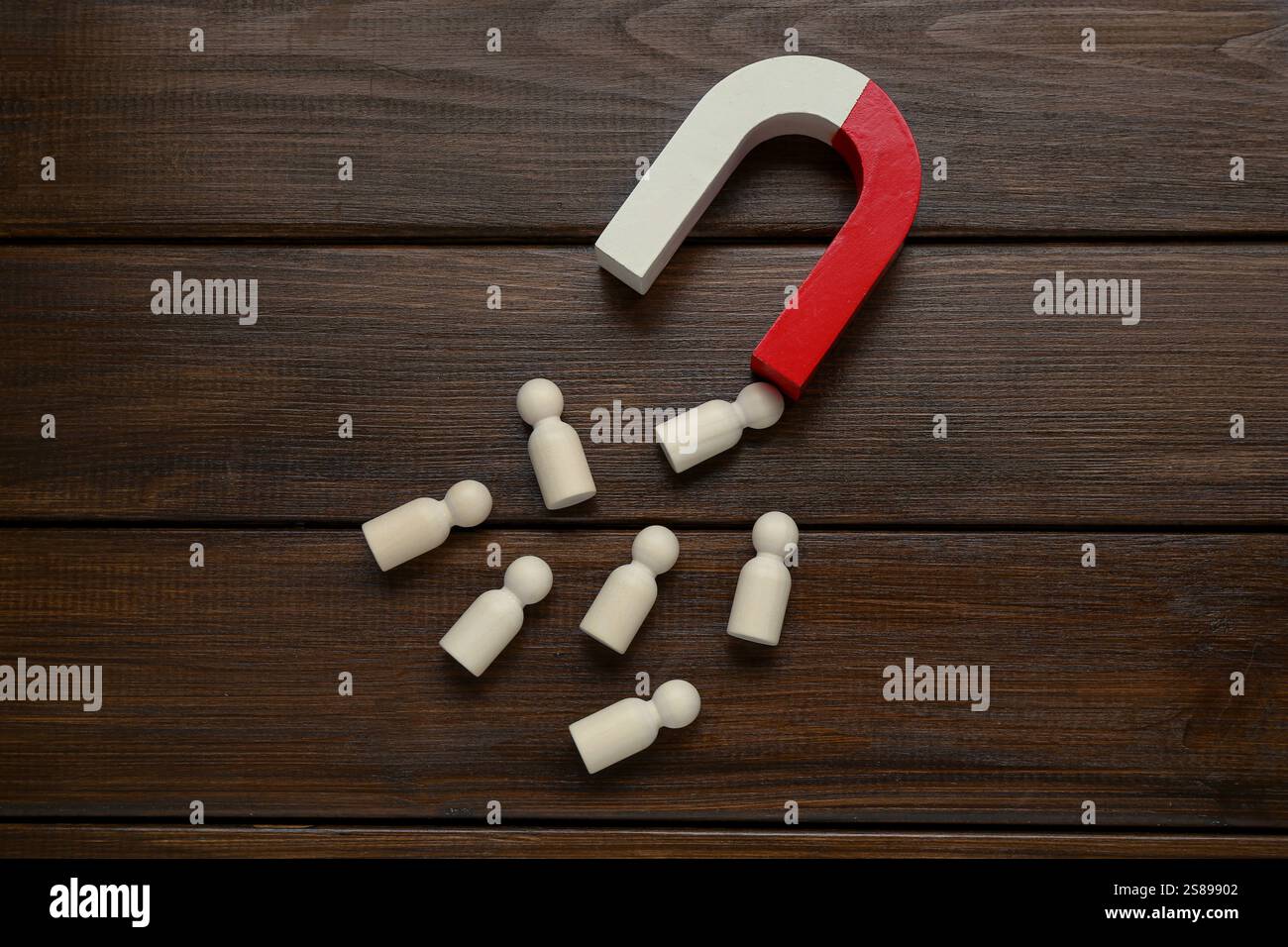 Magnet attracting human figures on wooden table, flat lay Stock Photo ...