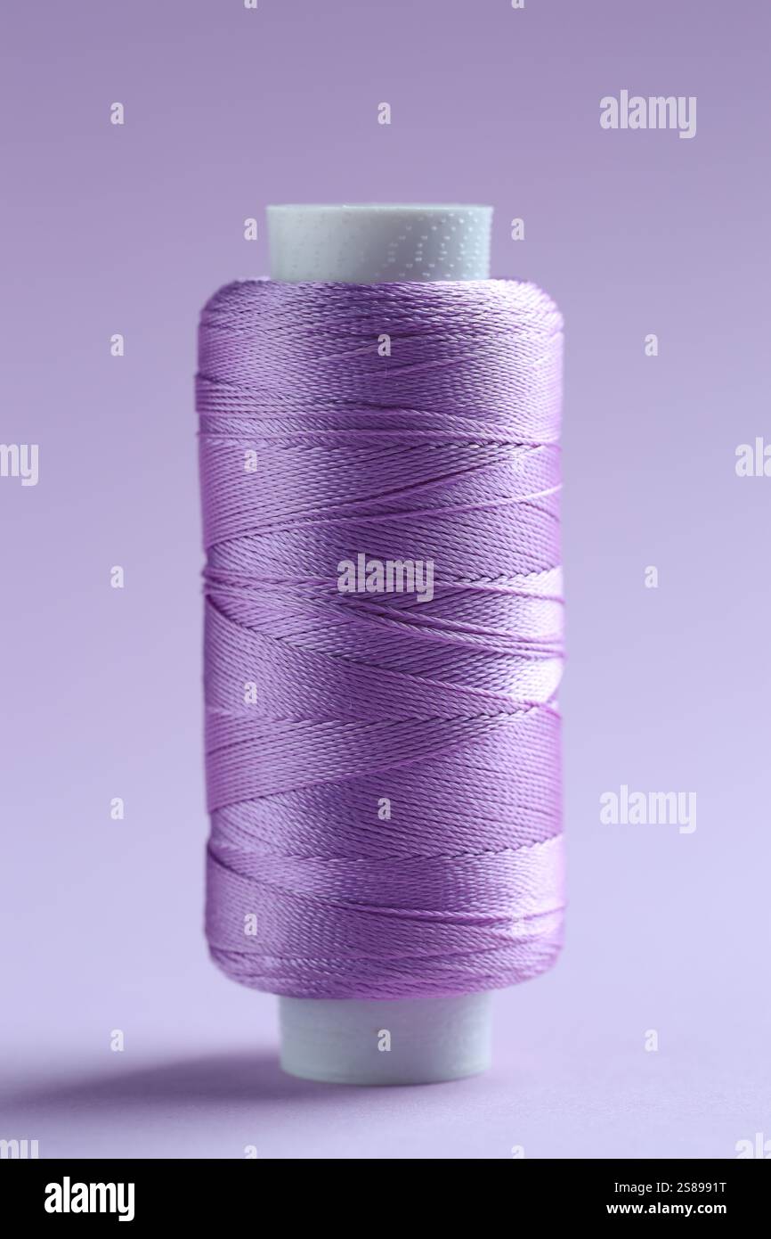 Spool of violet sewing thread on lilac background Stock Photo - Alamy
